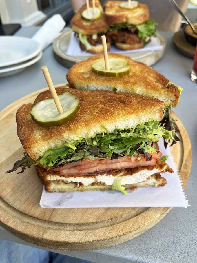 Not just any sandwich—a carefully constructed tower of crispy chicken, fresh greens, and that pickle spear standing guard like a delicious sentinel.