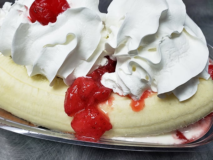 Banana splits aren't just desserts, they're architectural achievements—this one has enough whipped cream to make your childhood self weep with joy.