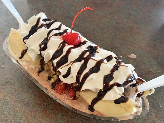 The banana split arrives like dessert royalty on its boat-shaped throne, chocolate drizzle creating edible pinstripes across whipped cream mountains.
