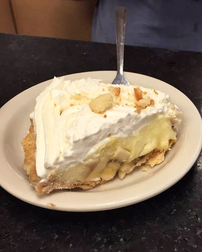 Banana cream pie with a meringue so tall it needs its own zip code. The fork stands at attention, ready for the sweet mission ahead.