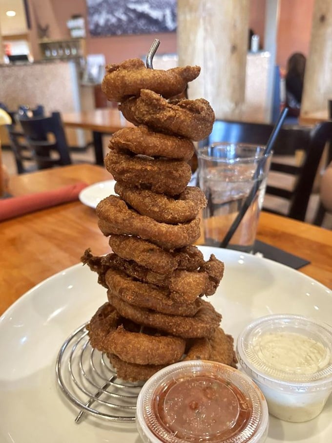 These blue corn onion rings aren't just stacked—they're practically performing a balancing act of crispy, golden perfection with dipping sauces standing by.