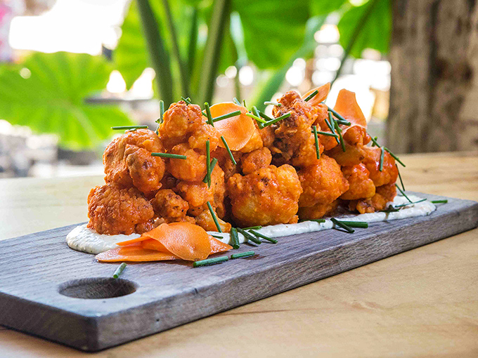 Buffalo cauliflower that makes vegetarians feel smug and carnivores question their life choices—crispy, saucy perfection on a wooden board.