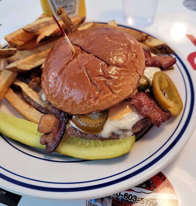 Not just any burger – this masterpiece stacks bacon, cheese, and pickles between a toasted bun with fries standing guard alongside.