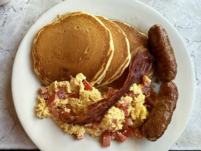 Three pancakes, two sausages, scrambled eggs, and bacon – because sometimes more really is more, and that's beautiful.