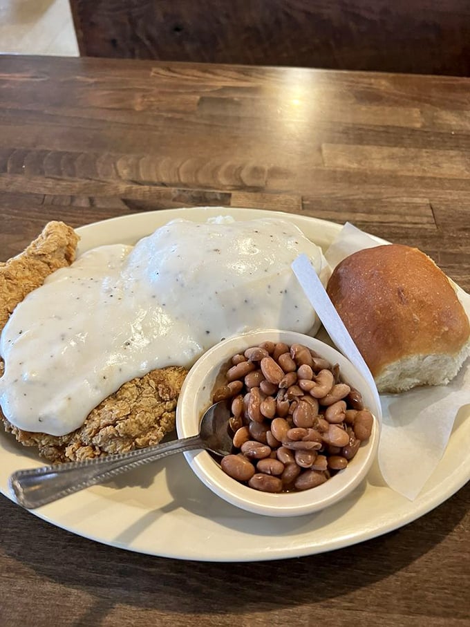 Chicken fried steak swimming in pepper-flecked gravy alongside pinto beans that have clearly been simmering since sunrise – Southern comfort on a plate. 