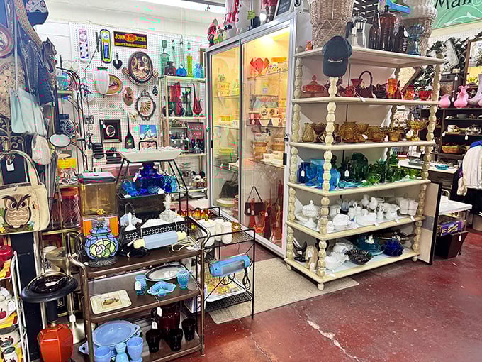 Color-coded glassware creates a rainbow of nostalgia. From cobalt blue bottles to milk glass figurines, each shelf holds memories waiting to be adopted.