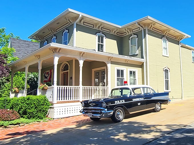 This sunshine-yellow Victorian house, complete with vintage police car, isn't a movie set—it's just another Tuesday in Chagrin Falls' picture-perfect historic district.
