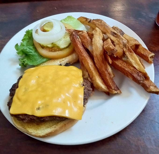 The cheeseburger arrives like a yellow-crowned monarch, ruling over hand-cut fries with the confidence of Southern royalty.