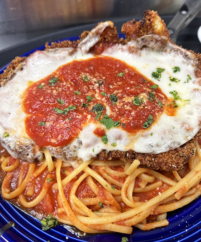 Not your nonna's chicken parm! This crispy masterpiece perches atop a sea of marinara-kissed pasta like the king of comfort food mountain.