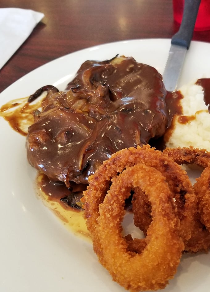 Gravy cascading over meat like a savory waterfall, with onion rings standing guard. Not all heroes wear capes—some wear gravy boats.