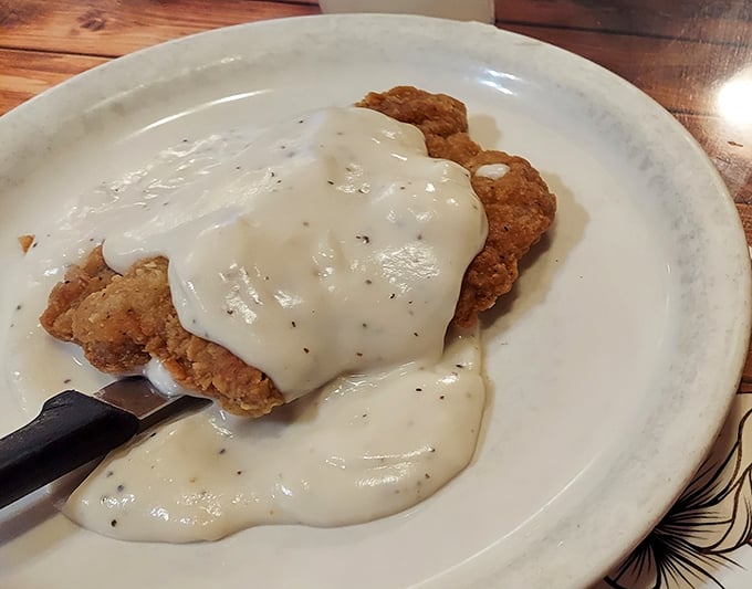 Country fried steak swimming in creamy pepper gravy—the breakfast equivalent of a warm hug from someone who truly understands comfort food.