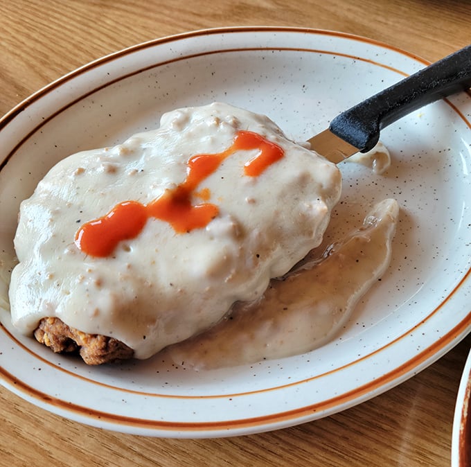 Country fried steak hiding beneath a blanket of gravy so good you'll want to write it a thank-you note. That splash of hot sauce? Chef's kiss.