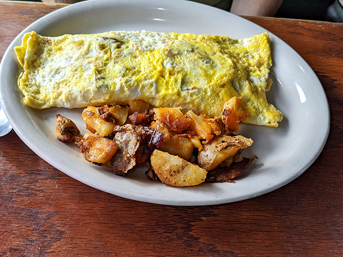 An omelet that doesn't just sit on the plate—it commands attention with its perfect fold and generous filling, like a letter from breakfast heaven.