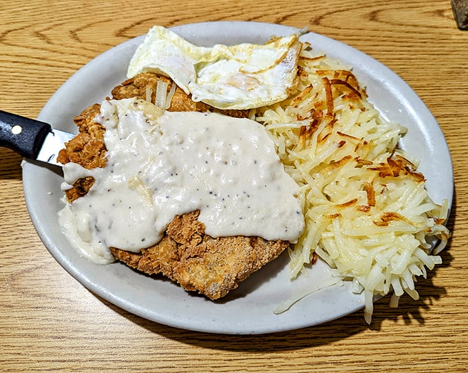 Country fried steak wearing its gravy coat with pride, while hash browns stand at attention nearby – a breakfast alliance that's never let anyone down.