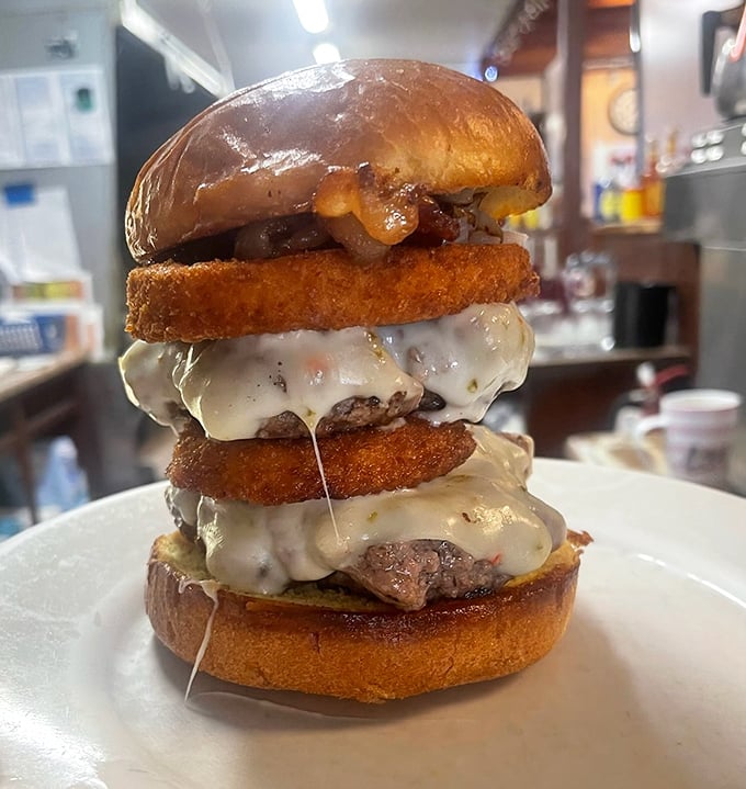 Not just a burger, but a towering monument to indulgence. Those onion rings aren't garnish—they're essential architecture in this savory skyscraper.