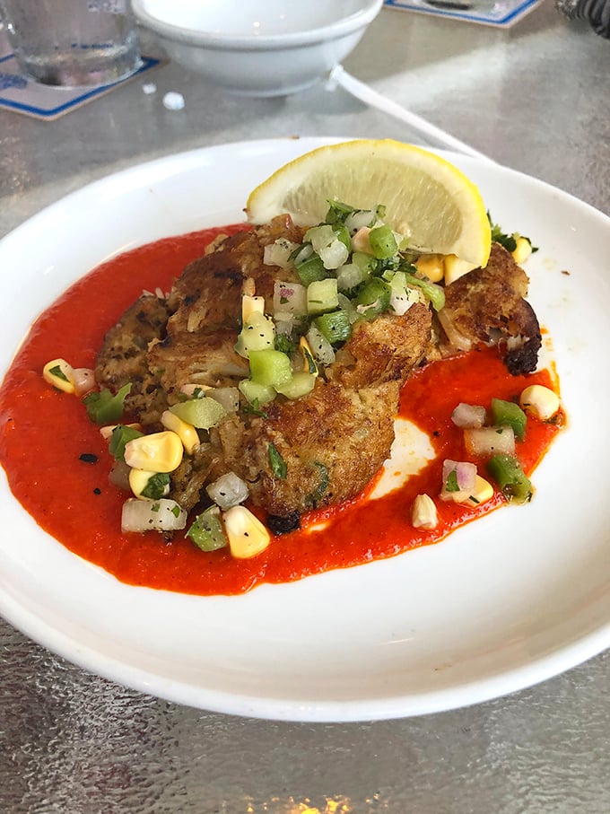 This crabcake doesn't hide behind fillers—it struts on a runway of vibrant sauce with corn confetti celebrating its arrival.