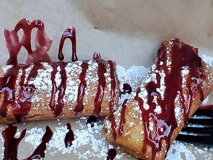 Deep-fried cheesecake drizzled with raspberry sauce—because regular cheesecake wasn't indulgent enough. The powdered sugar snowfall is just showing off at this point.