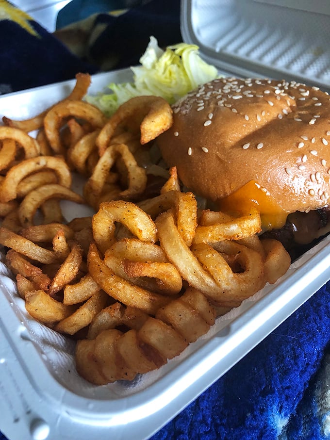 The classic cheeseburger and curly fries combo—where sesame seeds meet melted cheese in a dance as old as diners themselves. Simple pleasures, perfectly executed.