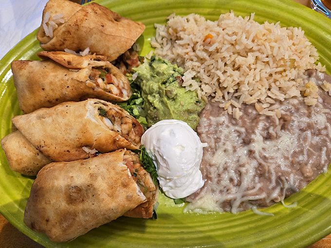 These flautas aren't just rolled, they're architectural achievements—crispy cylinders flanked by the holy trinity of Mexican sides: rice, beans, and sour cream.