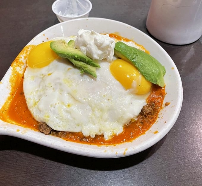 These eggs aren't just sitting on enchiladas—they're crowning them like royalty, with avocado slices as the royal attendants.