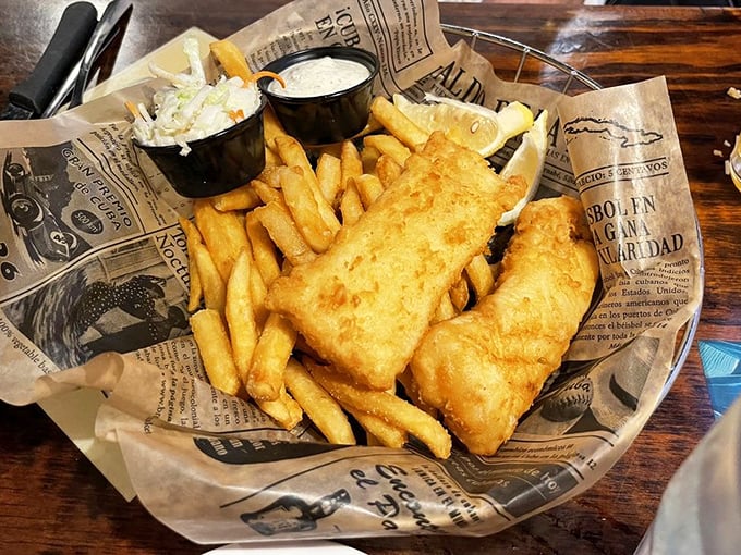 Fish and chips done right—crispy, golden batter protecting flaky white fish, served on newspaper because some traditions are worth keeping.