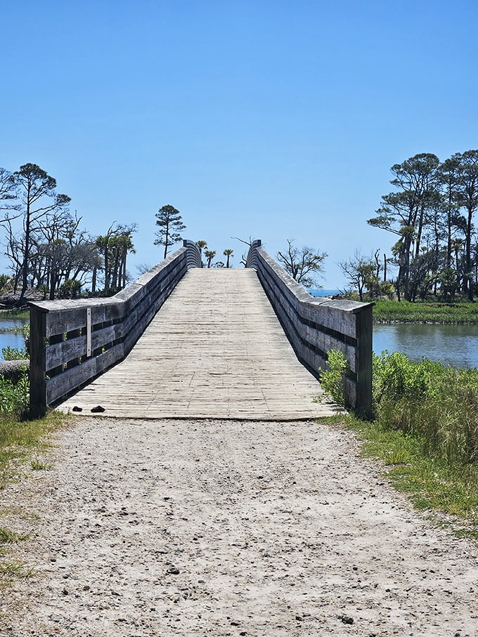 This wooden bridge doesn't just connect two pieces of land—it's a portal between everyday life and coastal tranquility.