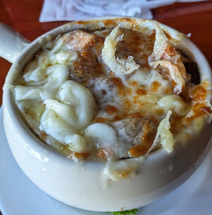 This isn't just French onion soup—it's a volcanic cheese eruption with sweet caramelized onions hiding beneath like delicious magma. Spoon-breaking cheese pull guaranteed.