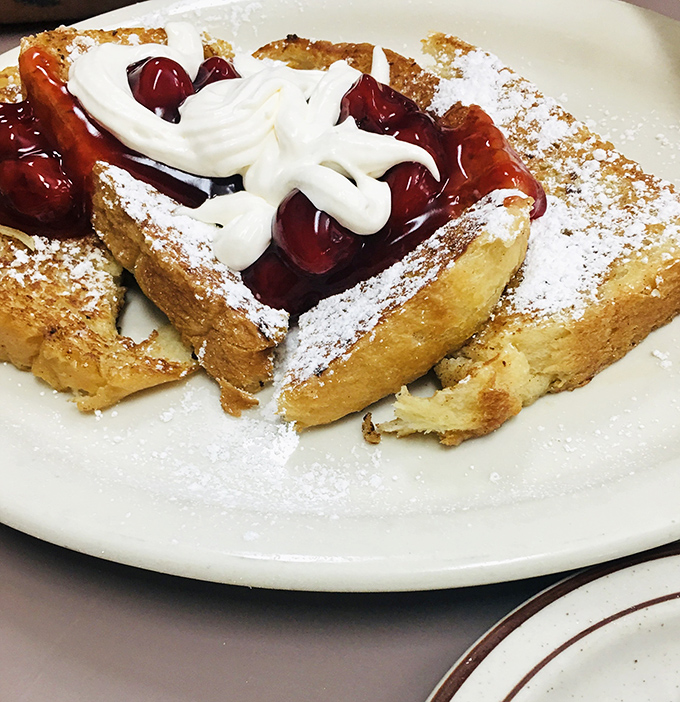 French toast that deserves its own national holiday. Those cherries aren't just toppings—they're ruby jewels crowning breakfast royalty.