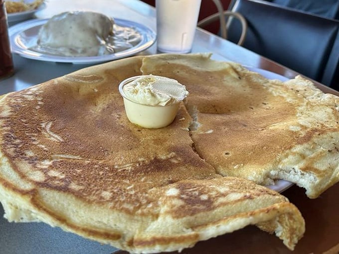 This pancake isn't just big – it's the size of a hubcap with butter melting into its golden surface like a sunrise over the Arizona desert.