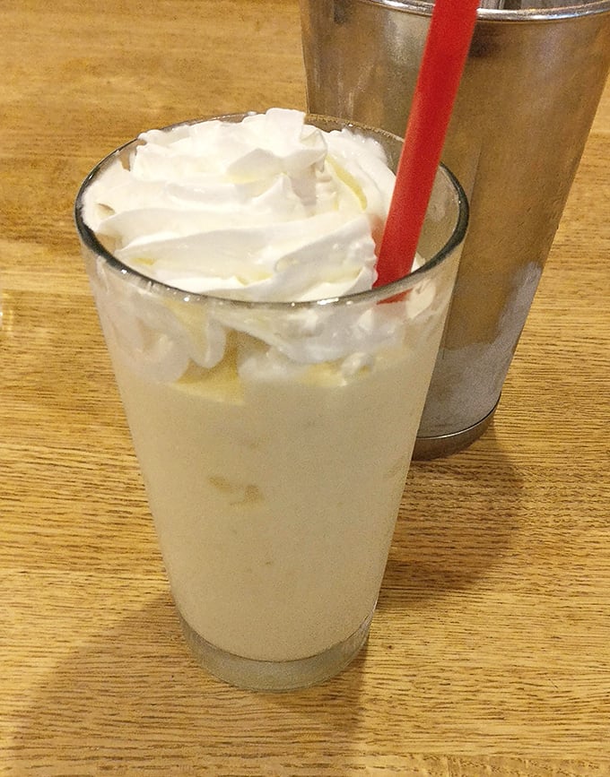 The milkshake that launched a thousand return visits, served old-school style with the mixing cup alongside—because one glass is never enough.