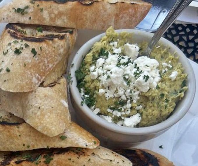 This isn't just hummus – it's a creamy canvas of chickpea goodness topped with feta, served with perfectly charred flatbread for dipping adventures.