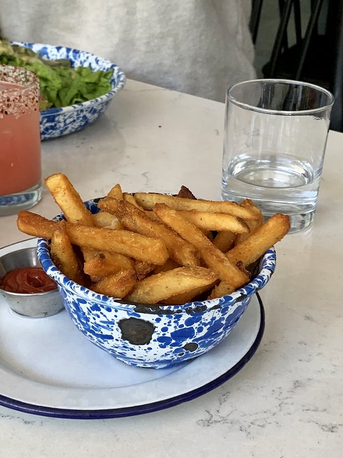 Golden, crispy home fries served in signature blue-speckled bowls—simple perfection that proves sometimes the supporting actors steal the show.
