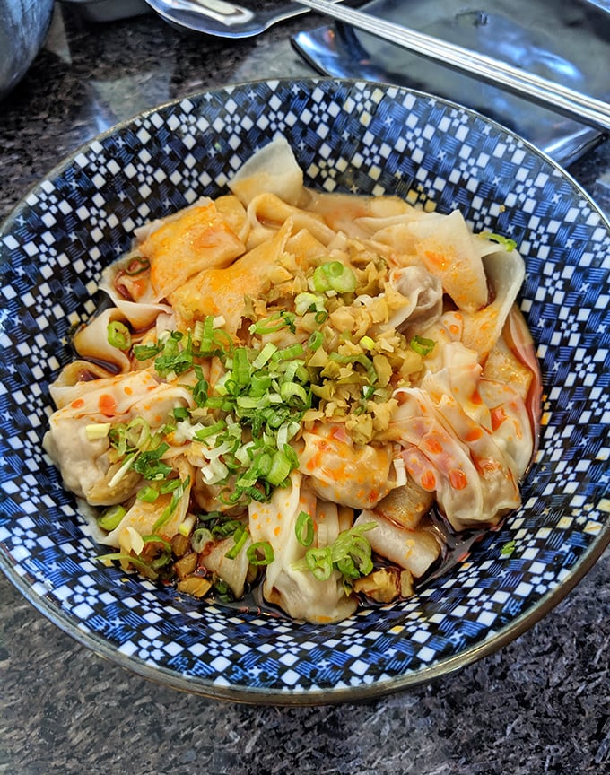 These delicate wontons swim in a sea of flavor, topped with vibrant herbs and scallions—proof that good things come in small packages.