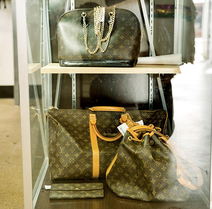 Designer dreams within reach! Louis Vuitton bags displayed behind glass—the thrift store equivalent of finding a unicorn in your backyard.