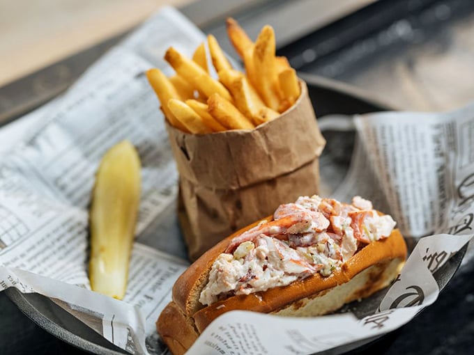 The lobster roll arrives like a celebrity – unpretentious yet commanding attention, with chunks of sweet meat barely contained by its toasted vessel.