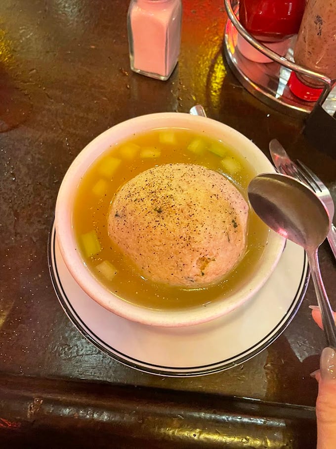 The matzo ball soup—golden broth cradling a perfect sphere of comfort. Penicillin might cure illness, but this cures the soul.