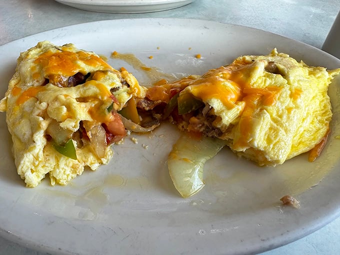 Breakfast alchemy at its finest! This overstuffed omelet bursts with melted cheese, fresh veggies, and savory meats – a morning masterpiece worth setting your alarm for.