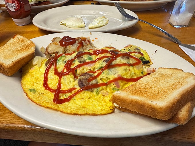 This isn't just any omelet—it's a fluffy yellow canvas painted with savory fillings and a bold ketchup signature that screams "vacation mode activated!"