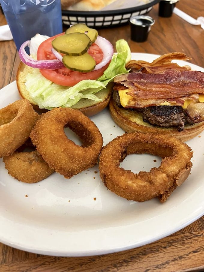 The burger comes dressed for success with all the fixings. Those golden onion rings aren't just sides—they're edible halos of happiness.