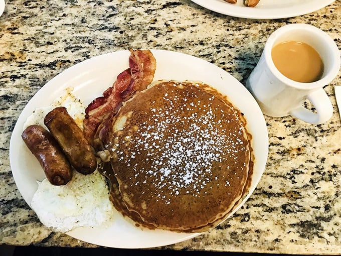 This isn't just a pancake—it's a fluffy canvas of possibility, dusted with powdered sugar and flanked by bacon that's achieved crispy-chewy perfection.