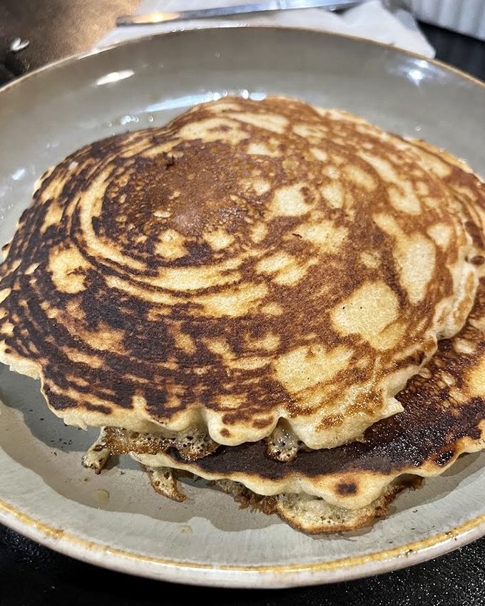These pancakes have achieved that mythical balance—crisp edges giving way to pillowy centers that absorb syrup like they were born for it.