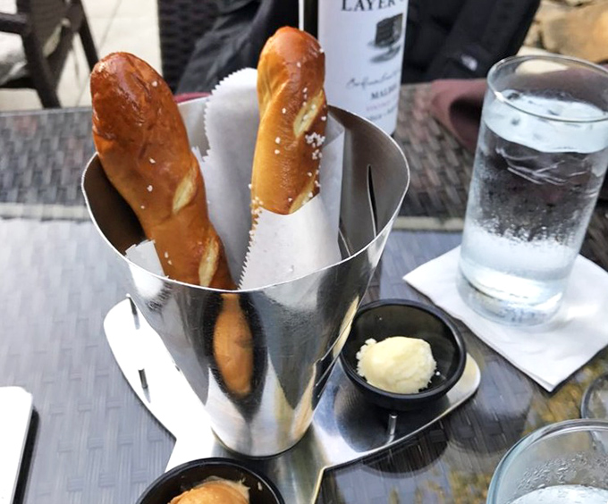 Pretzel breadsticks standing at attention in their metal vessel—warm, salty soldiers awaiting their orders to march toward butter.