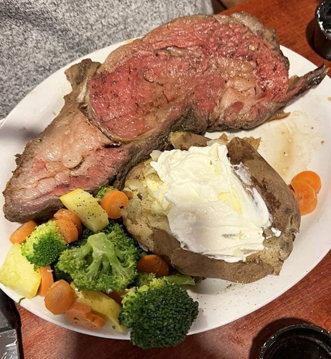Prime rib cooked to that magical sweet spot between rare and medium-rare, with a loaded baked potato that's practically its own food group.