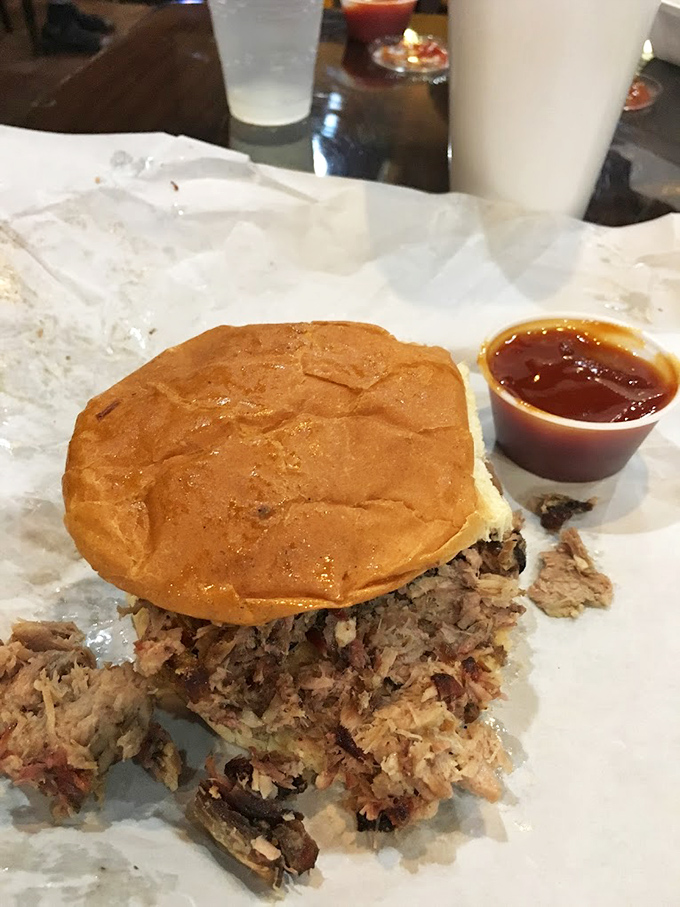 The pulled pork sandwich – where smoke meets sweet bun in perfect harmony. Notice how it's practically bursting with meat? That's not an accident.