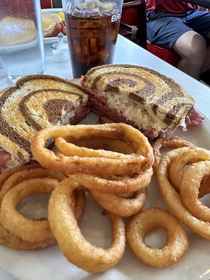 This Reuben isn't just a sandwich; it's architecture with flavor. Those onion rings? The golden halos of lunch perfection.