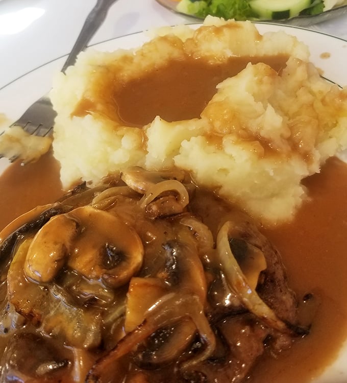 Not your cafeteria lady's Salisbury steak! This mushroom-smothered masterpiece with cloud-like mashed potatoes could make anyone homesick, even at home.