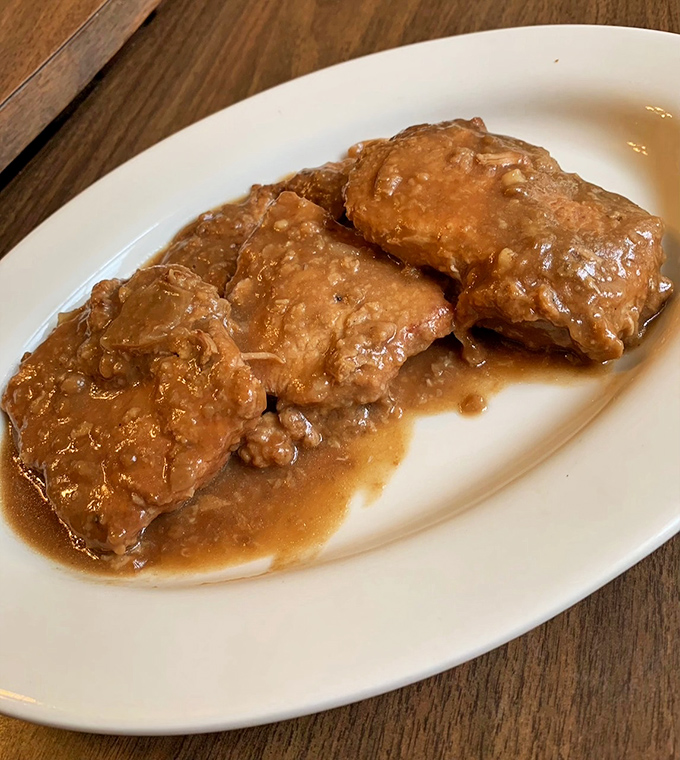 These smothered pork chops aren't just swimming in gravy—they're doing the backstroke in flavor country. Fork-tender doesn't begin to describe it.