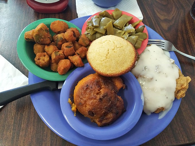 Southern comfort on a blue plate—crispy okra, cornbread, and country-fried something smothered in gravy. Diet plans come here to die glorious, delicious deaths.
