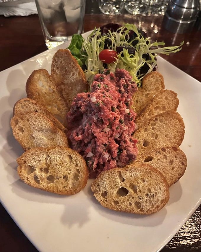 Steak tartare – where raw beef becomes an art form, surrounded by crisp toast points like a meaty sunflower in full bloom.