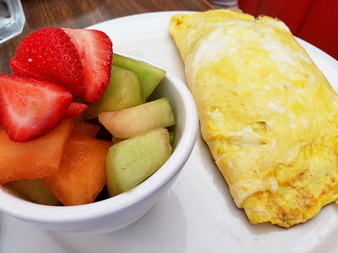 This isn't just an omelet—it's a golden envelope delivering a love letter of fresh vegetables alongside nature's perfect fruit salad.